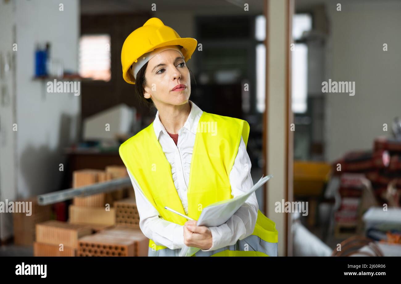 Female civil engineer making notes while controlling workflow at ...