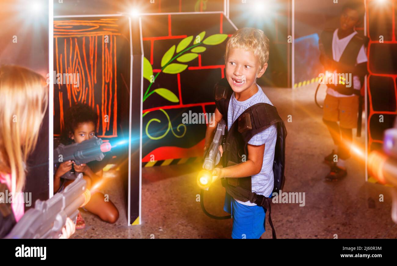 Emotional teen boy with laser pistol playing laser tag with friends on ...