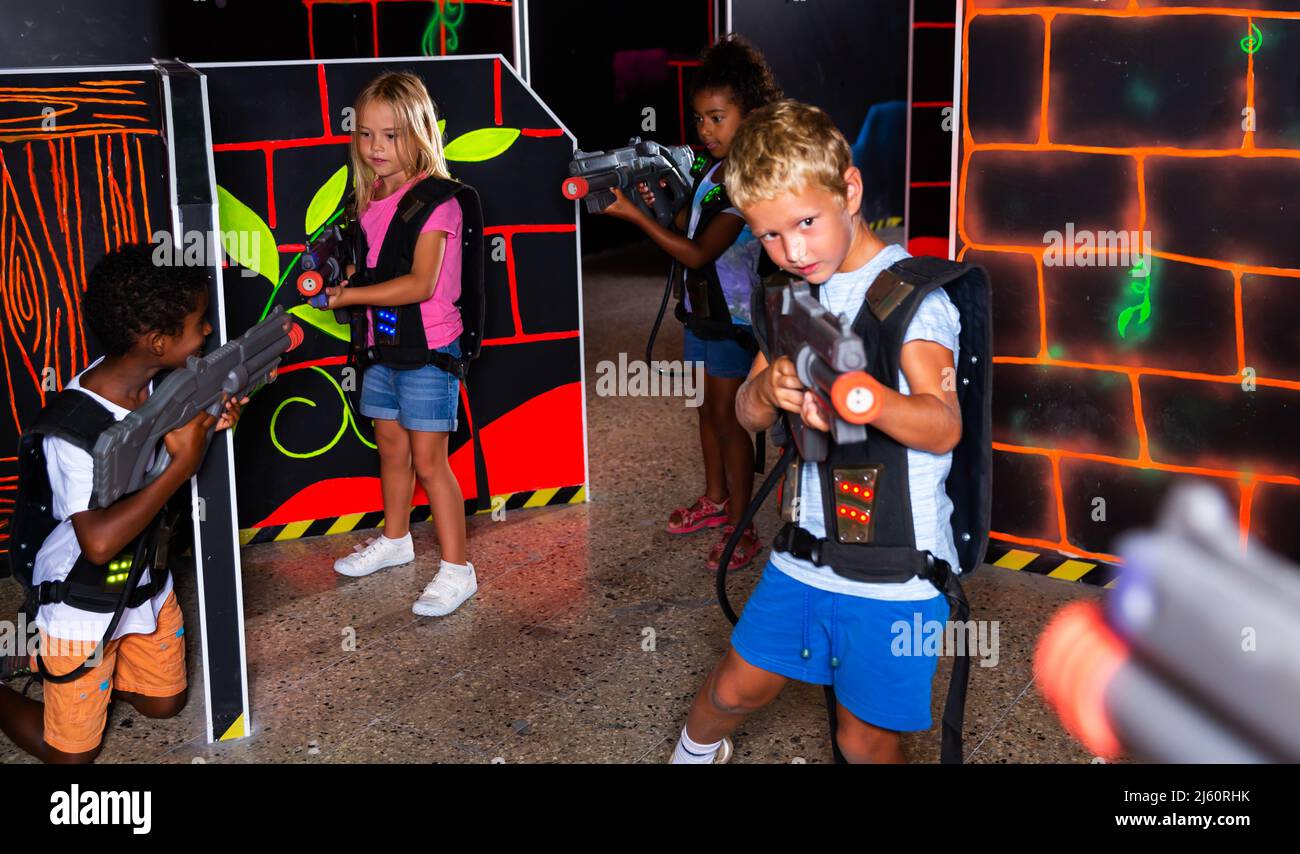 Emotional teen boy with laser pistol playing laser tag with friends on ...