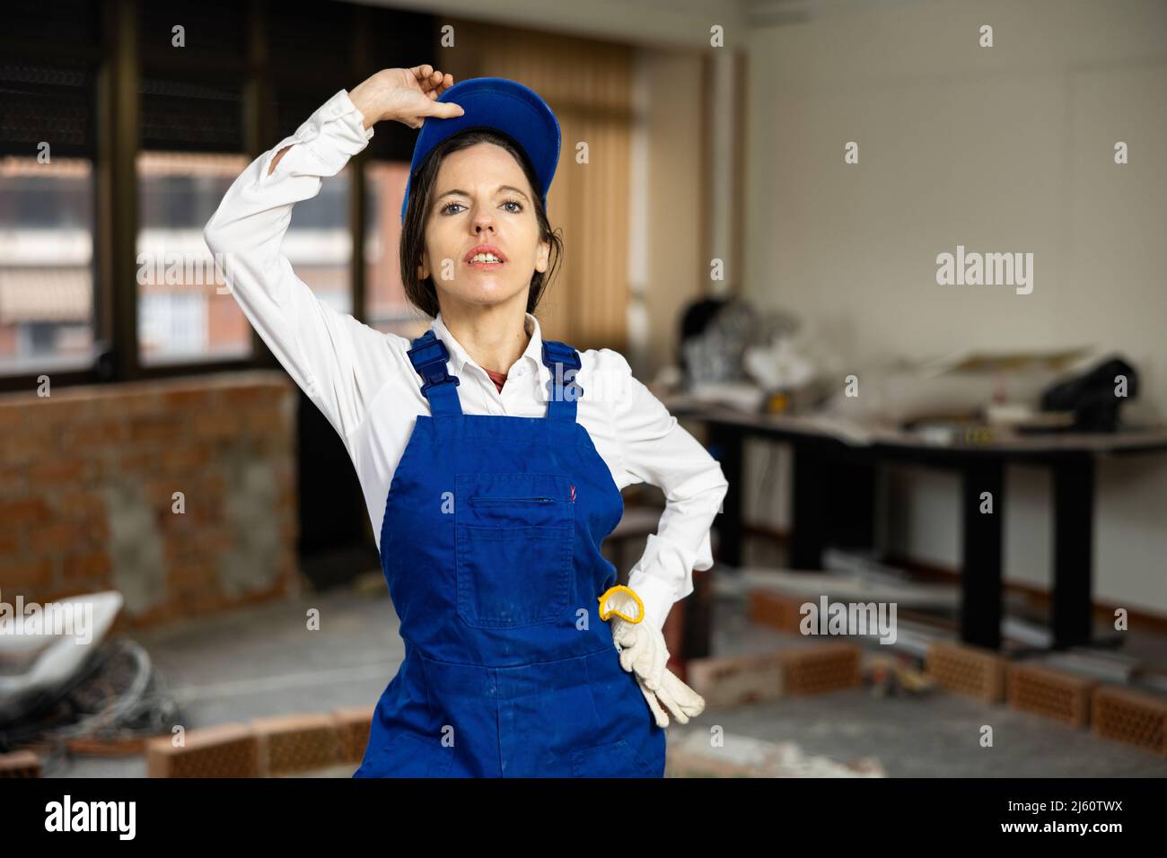 Woman foreman in blue overalls posing in house under construction Stock ...