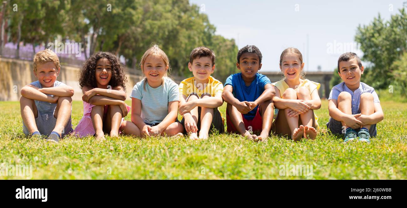 Happy children sitting on the green grass on day Stock Photo - Alamy