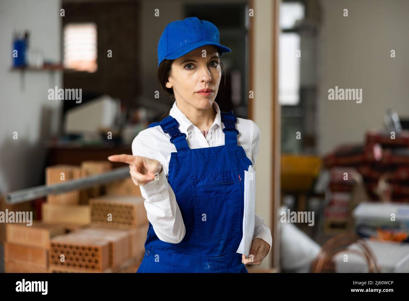 Strict female foreman instructing workers at construction site indoors ...