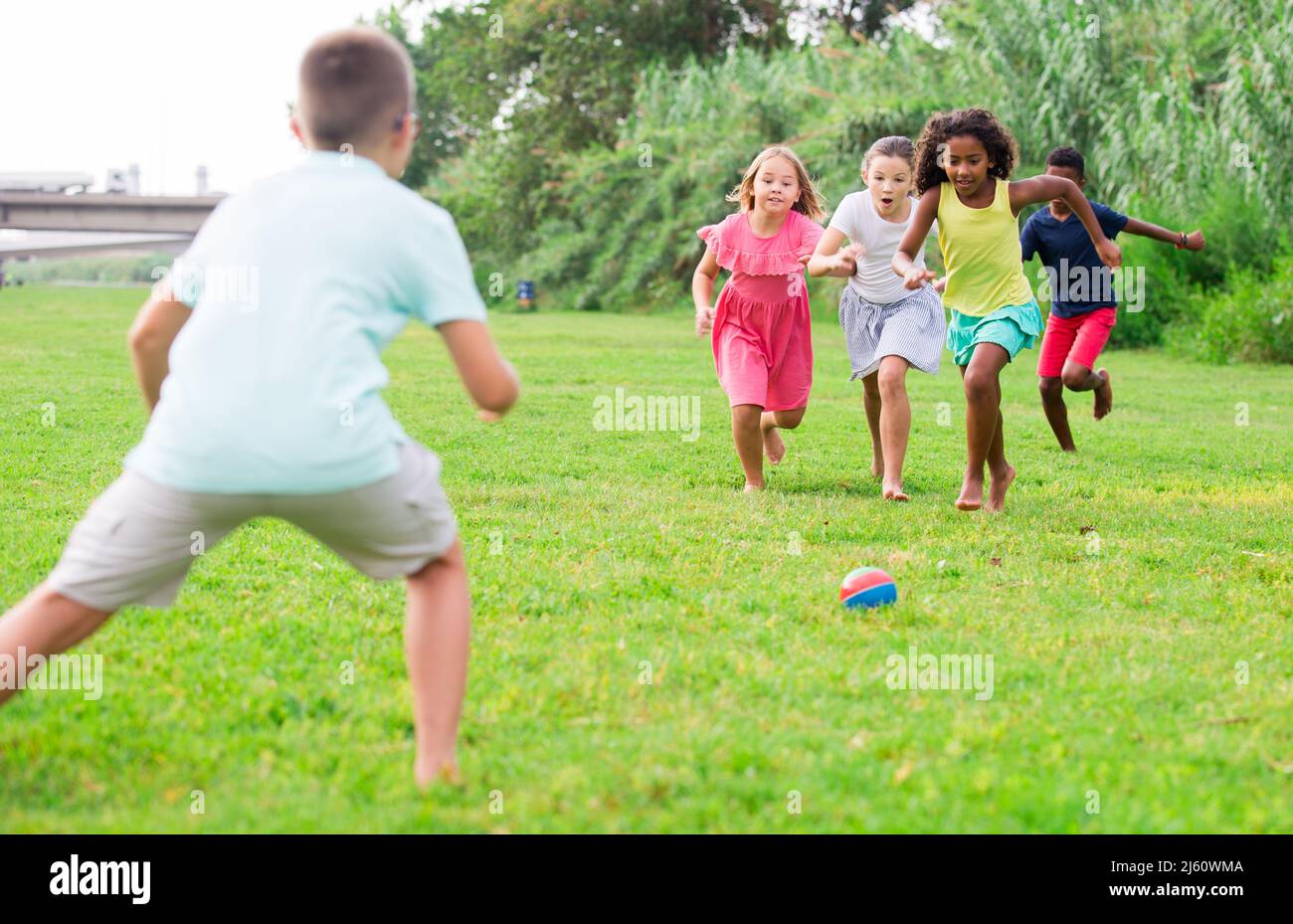 Cheerful tween friends playing with ball outdoors in summer Stock Photo ...