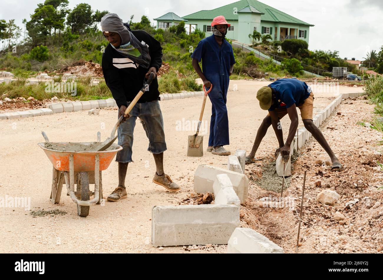 Workmen are building curve wall at the side of a road the is under ...