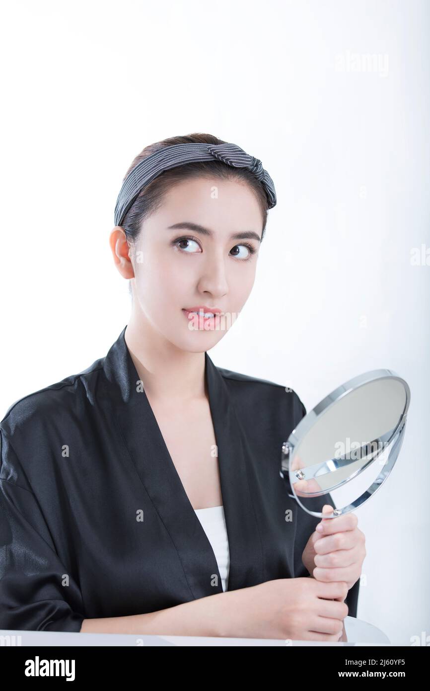 An elegant young and beautiful Chinese lady is looking at herself in ...