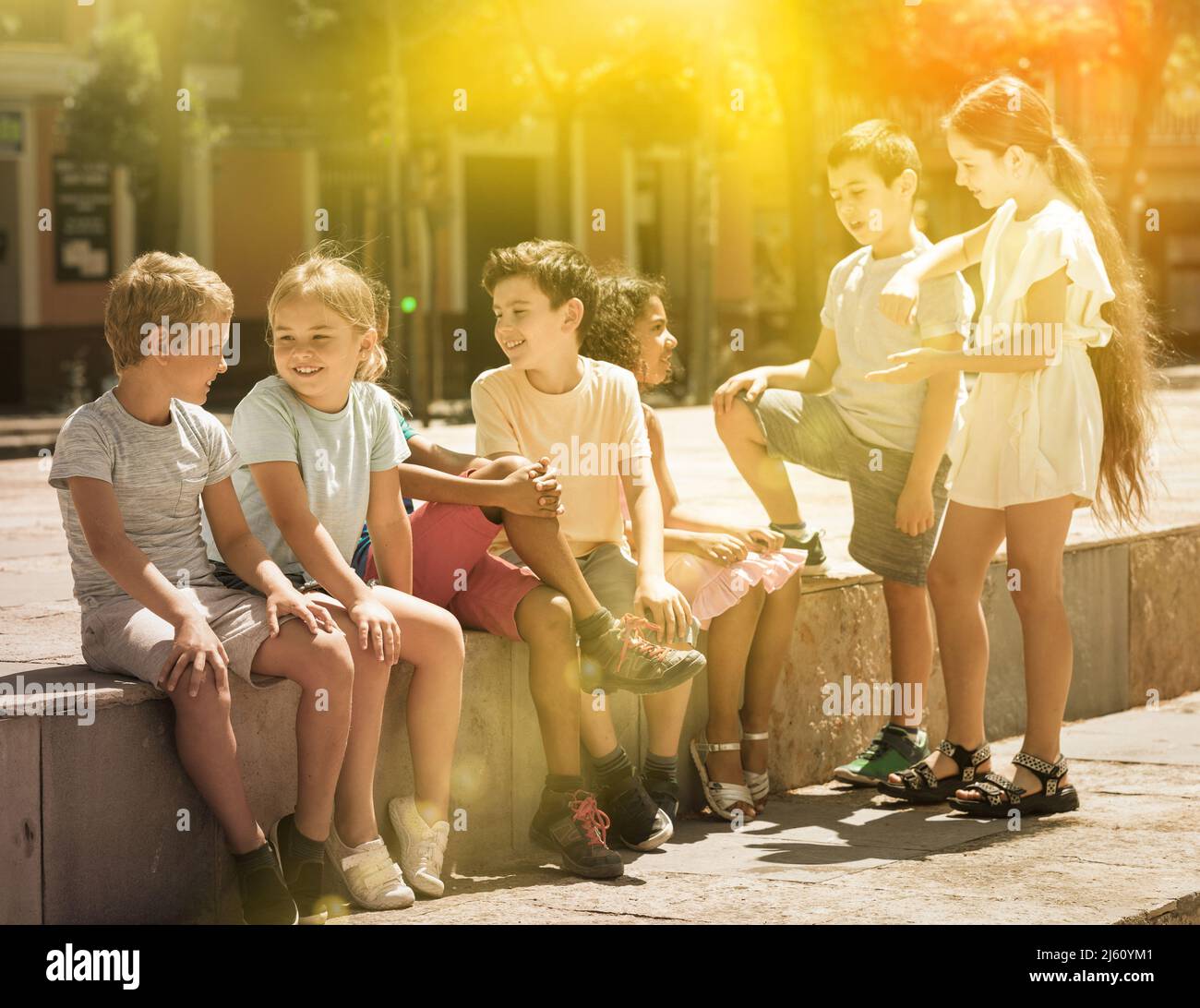 Positive children chatting together sitting at urban street Stock Photo ...