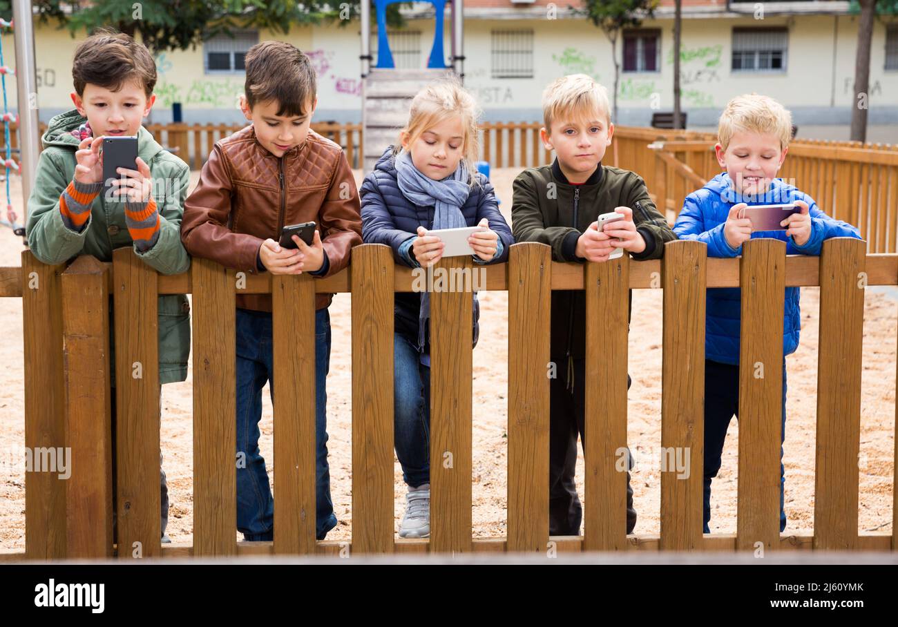 Kids playing with smartphones near wooden fence Stock Photo - Alamy