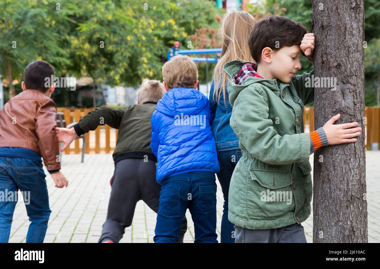 Boy playing hide and seek with friends Stock Photo - Alamy