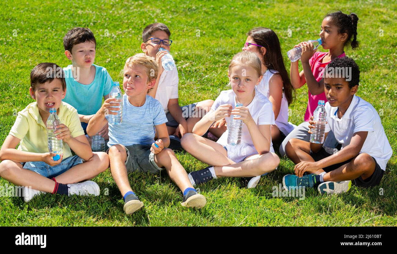 Group of children drink water from bottles on the summer lawn Stock ...