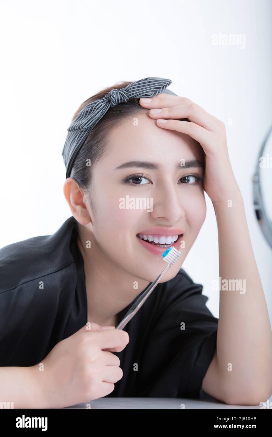 Young energetic Chinese woman using a toothbrush to clean and whitening ...
