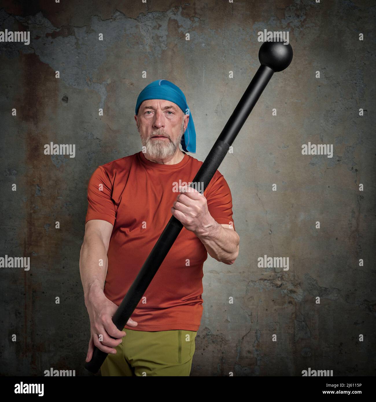 portrait of senior male exercising with a steel mace against a grunge ...
