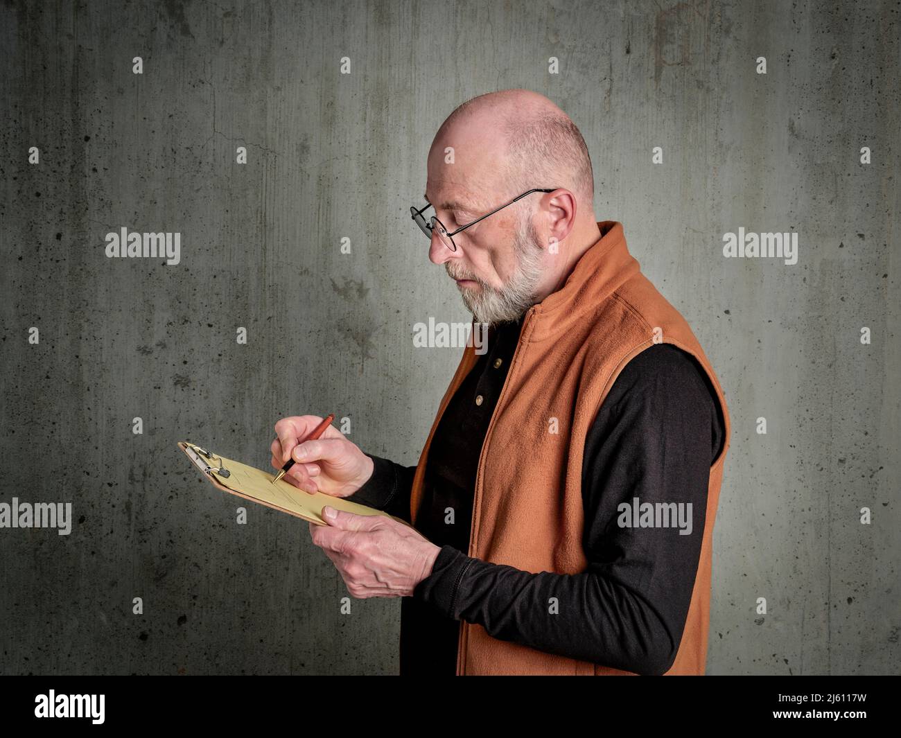 Head and shoulders portrait of a senior, bald and bearded man writing ...