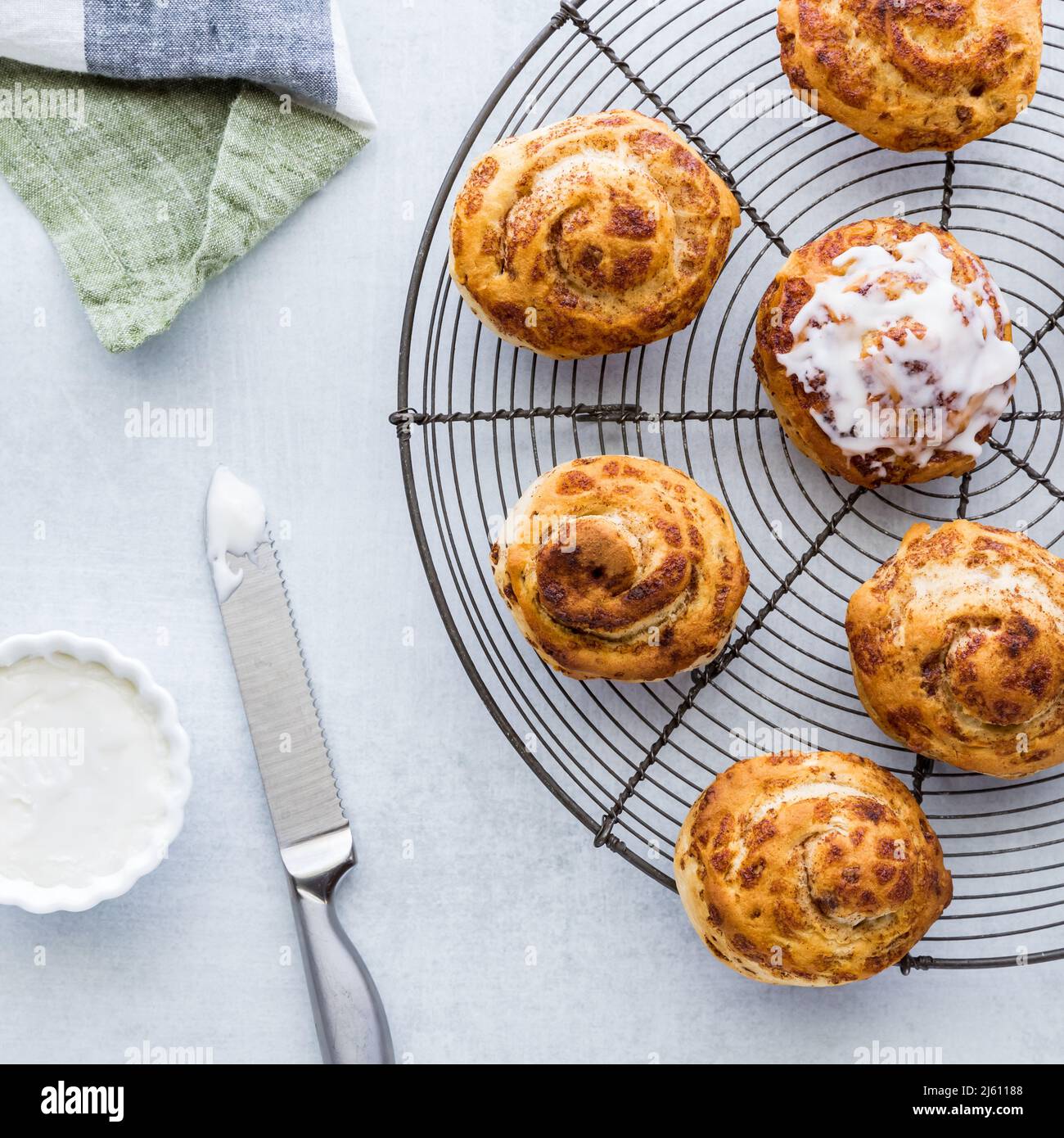 Top down view of cinnamon buns on a cooling rack served with cream ...