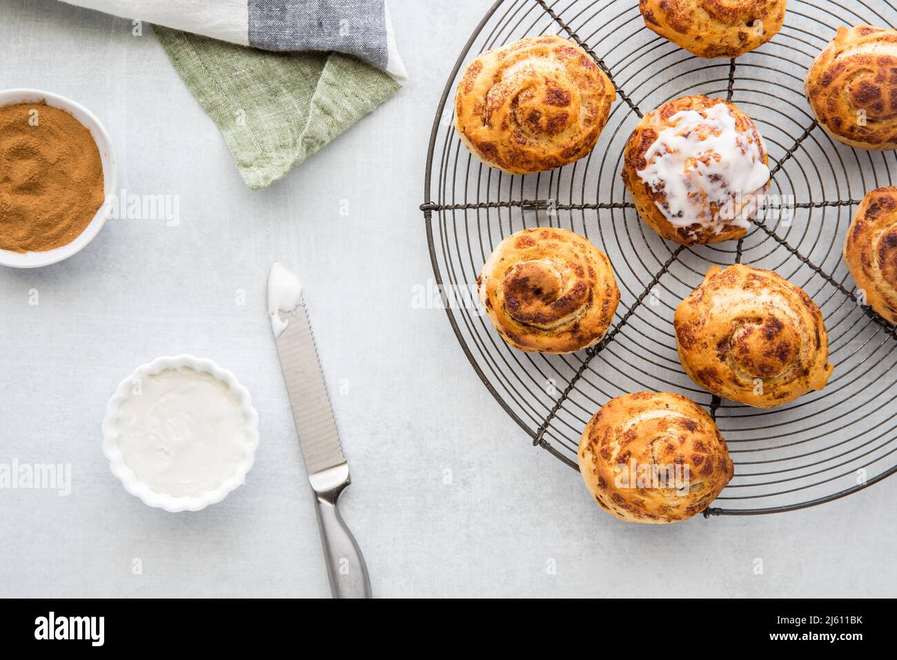 Top down view of cinnamon buns on a cooling rack served with cream ...