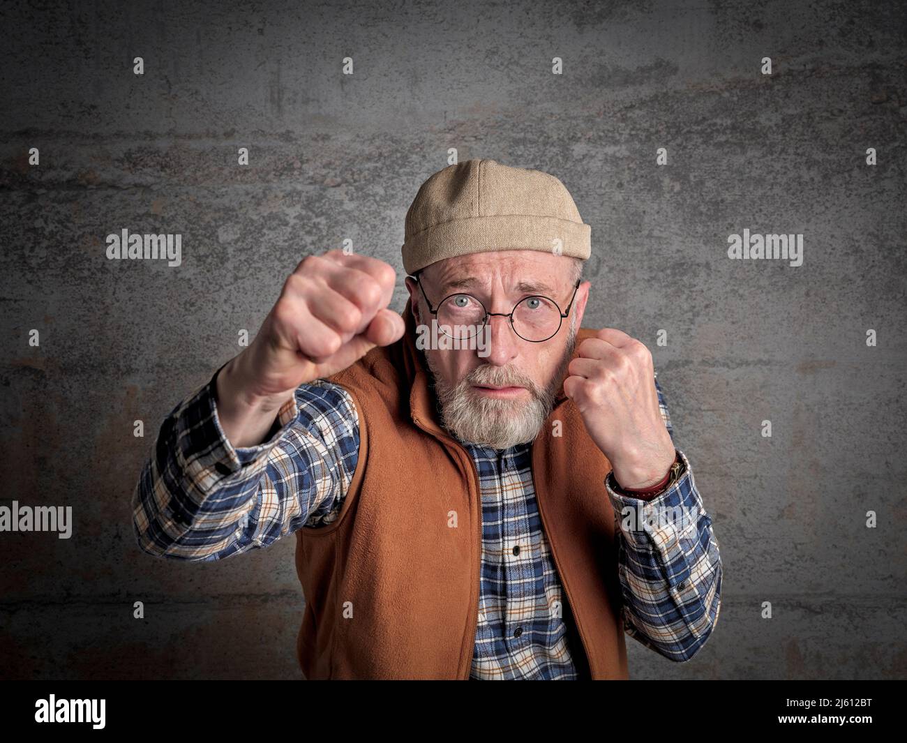 senior, bearded, scared man in boxing position is trying to defend ...