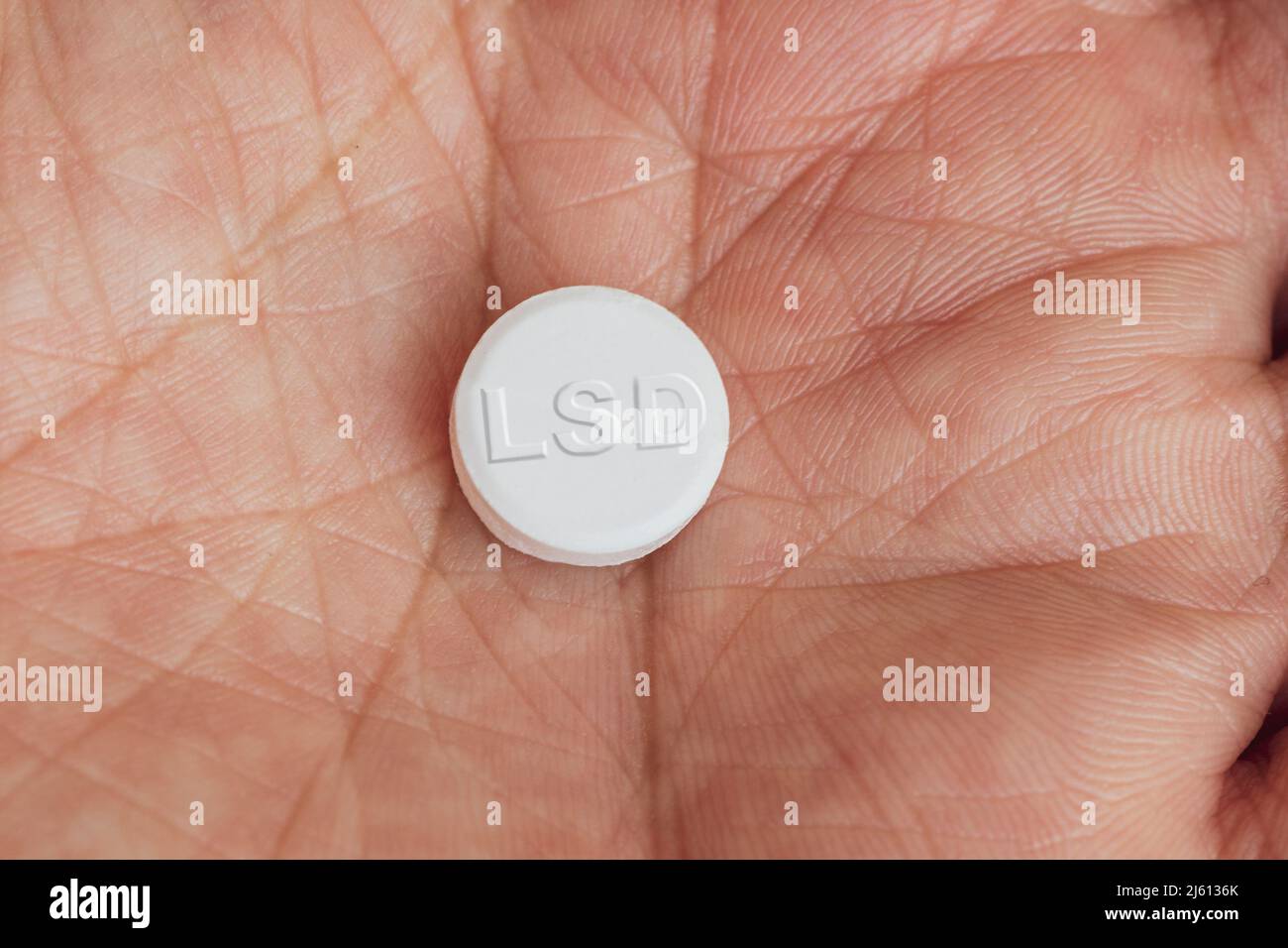 a white pill with LSD written on the palm of a man's hand. The concept ...