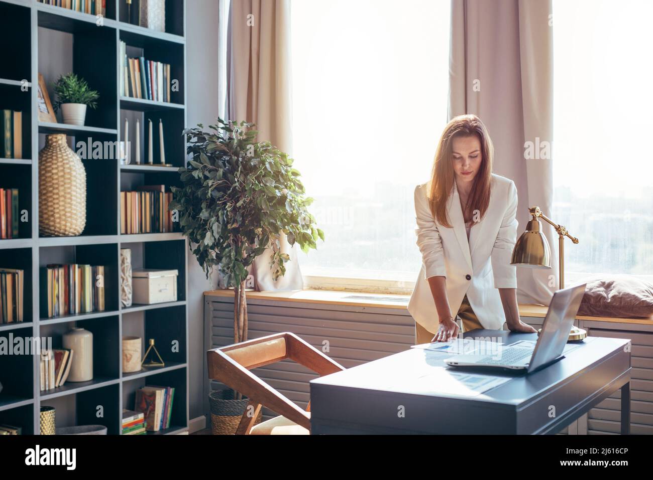 Woman clears the table after work or prepares for work by laying out ...