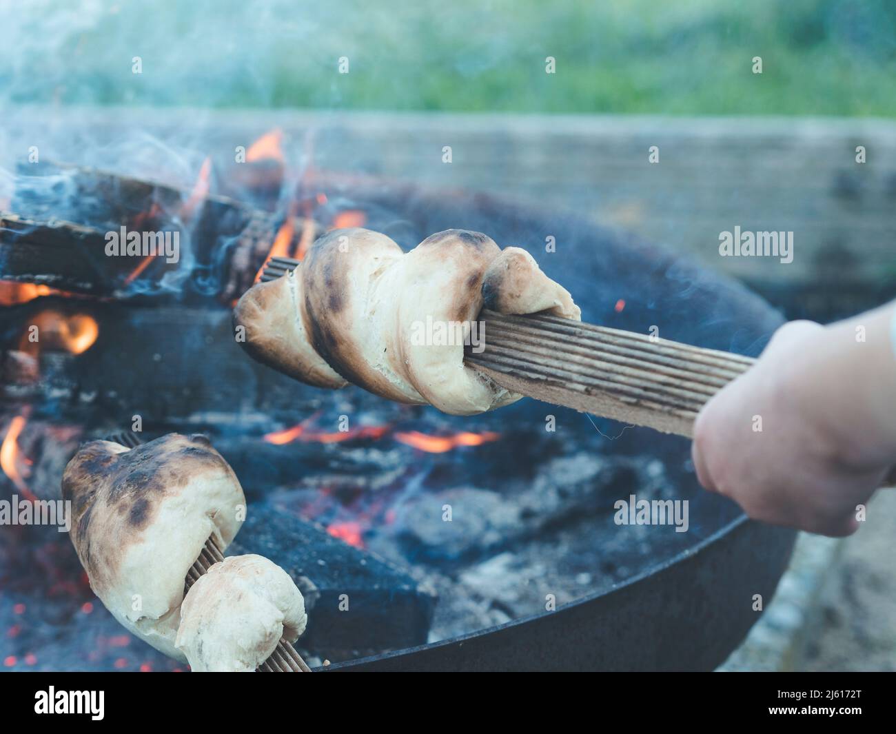 kids hand holding stick with stockbrot or twisted campfire stick bread ...