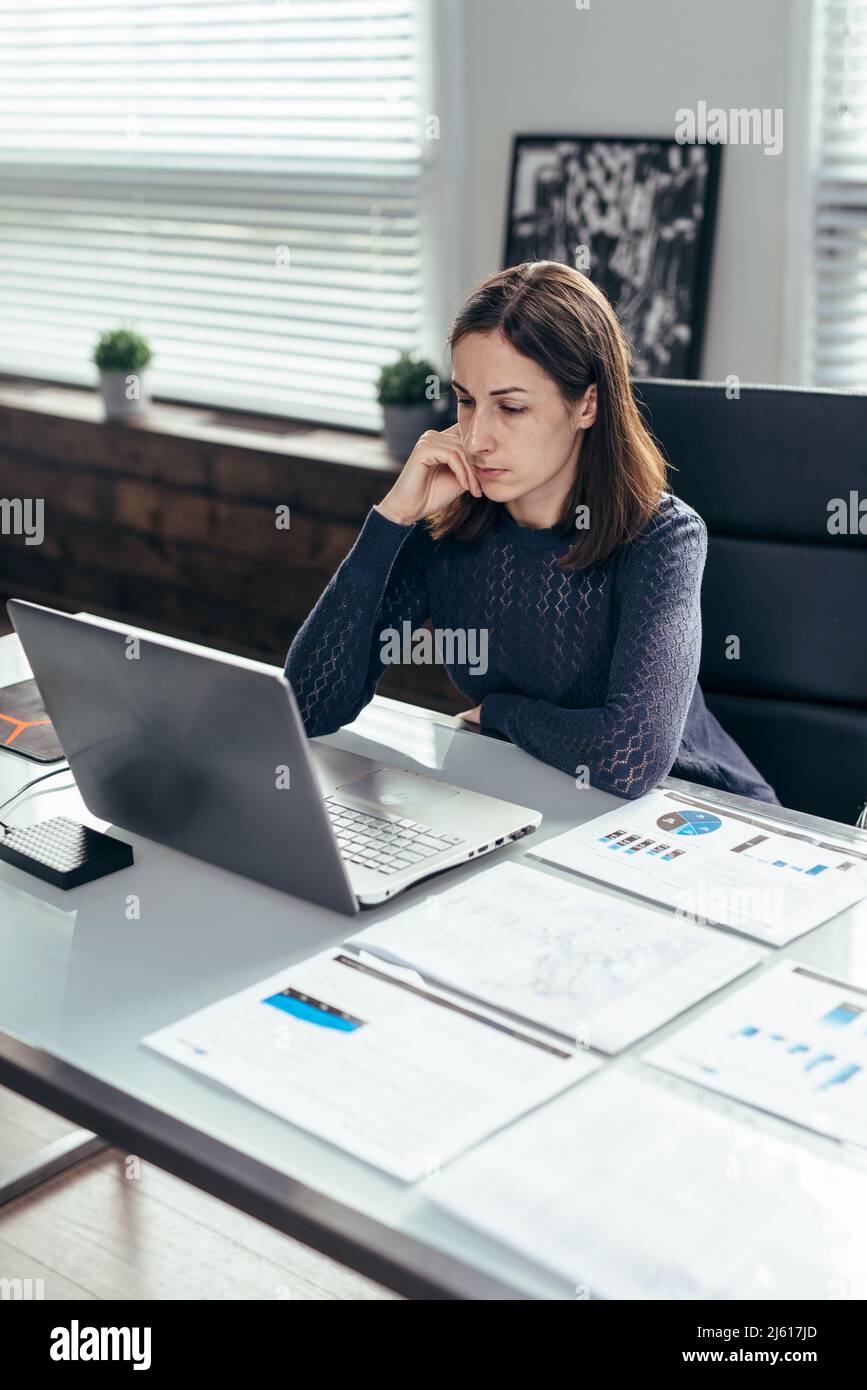 Woman in the office at her desk looks at the notebook screen Stock ...