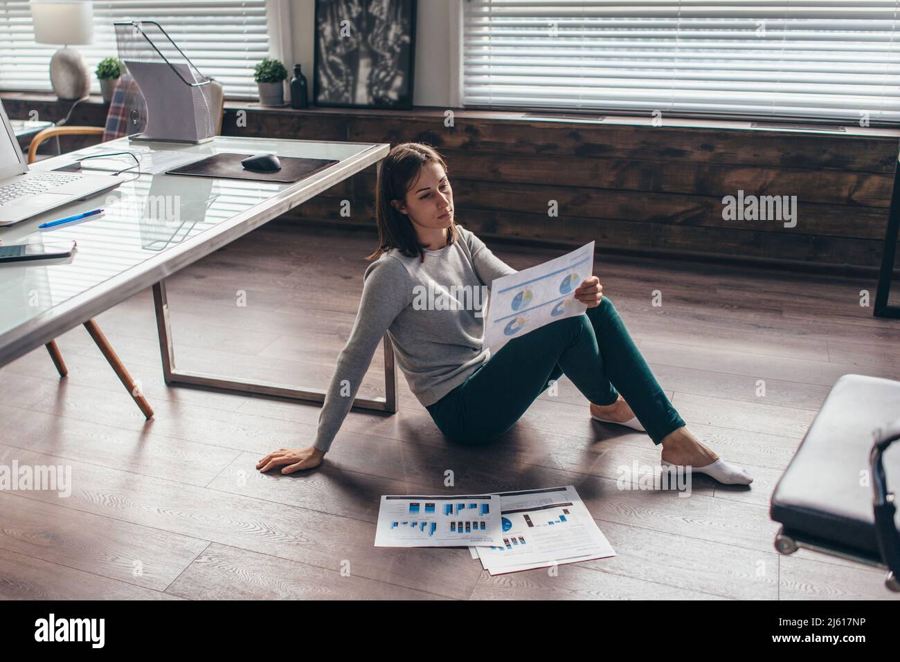 Female student sits on the floor and is learning. She has a paper in ...