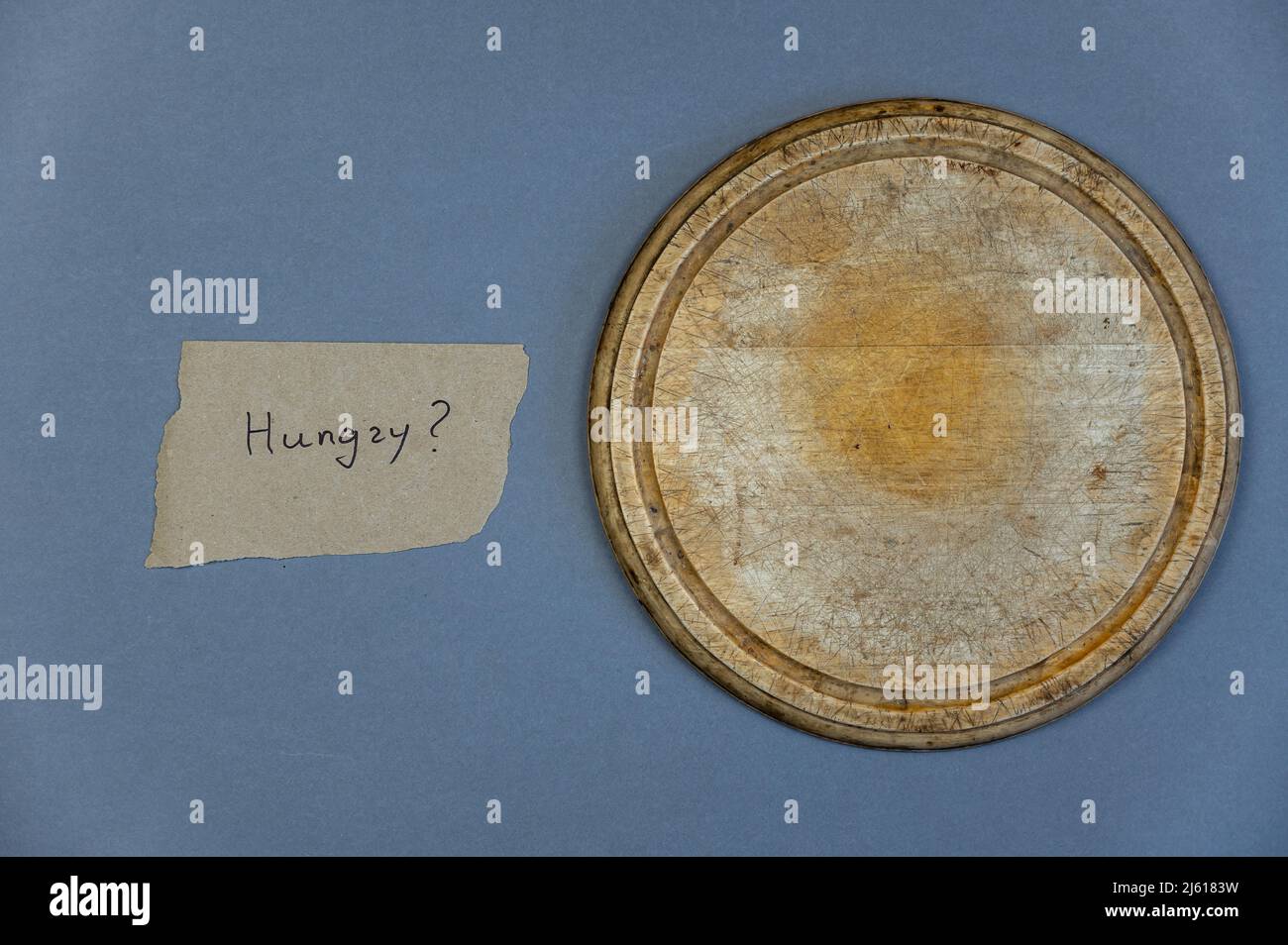 A round, empty wooden cutting board against a gray background. Scrap of ...