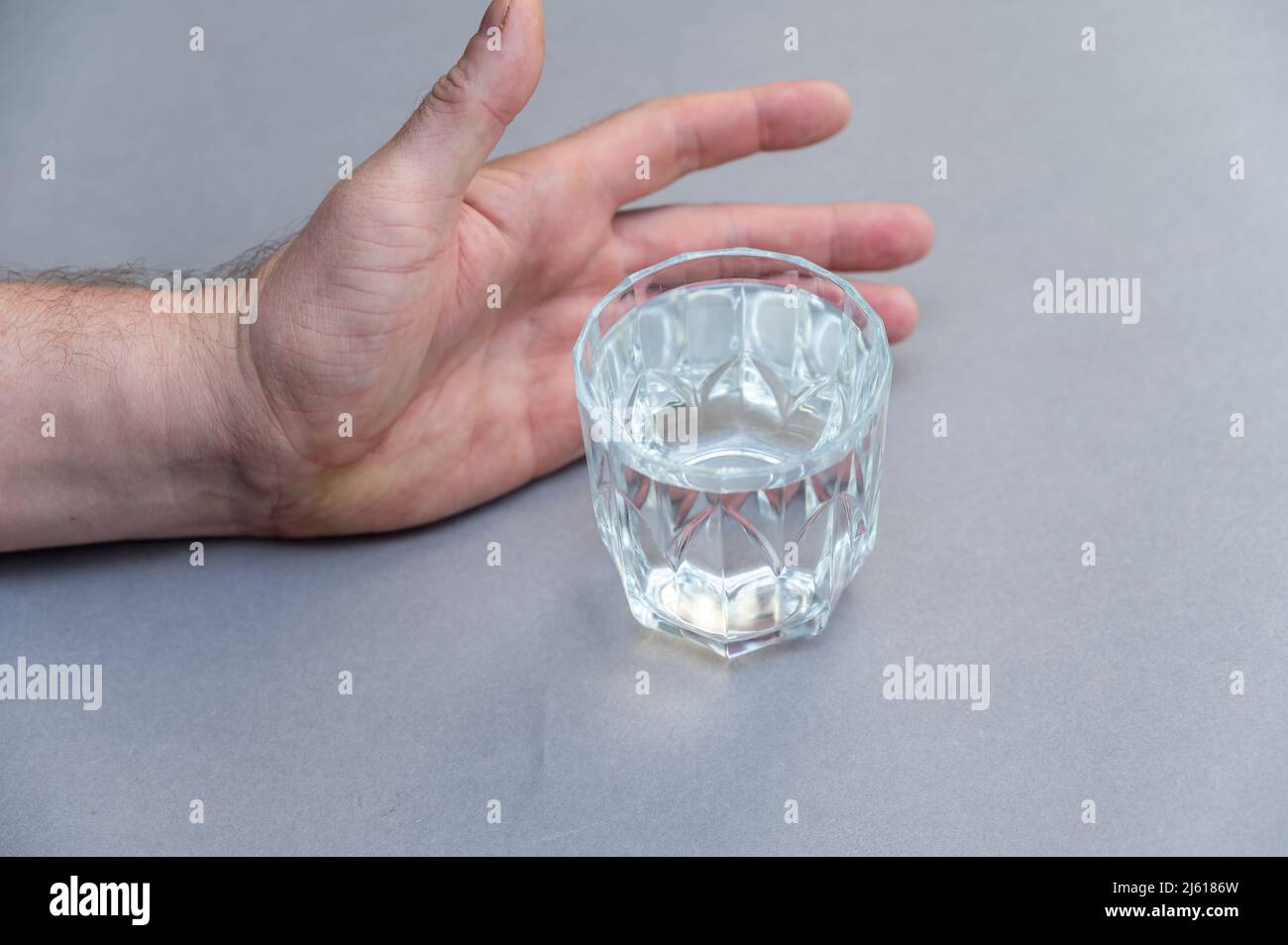 A man's hand intends to take a glass of water. A glass of clear ...