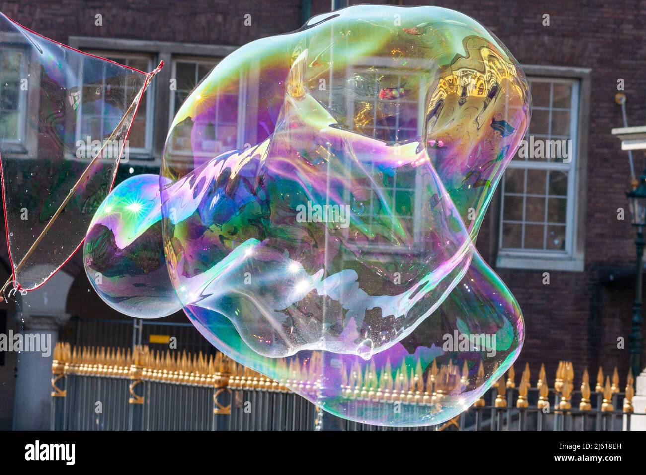 Gigantic soap bubbles shimmer and glimmer in the sun as colorful kids ...