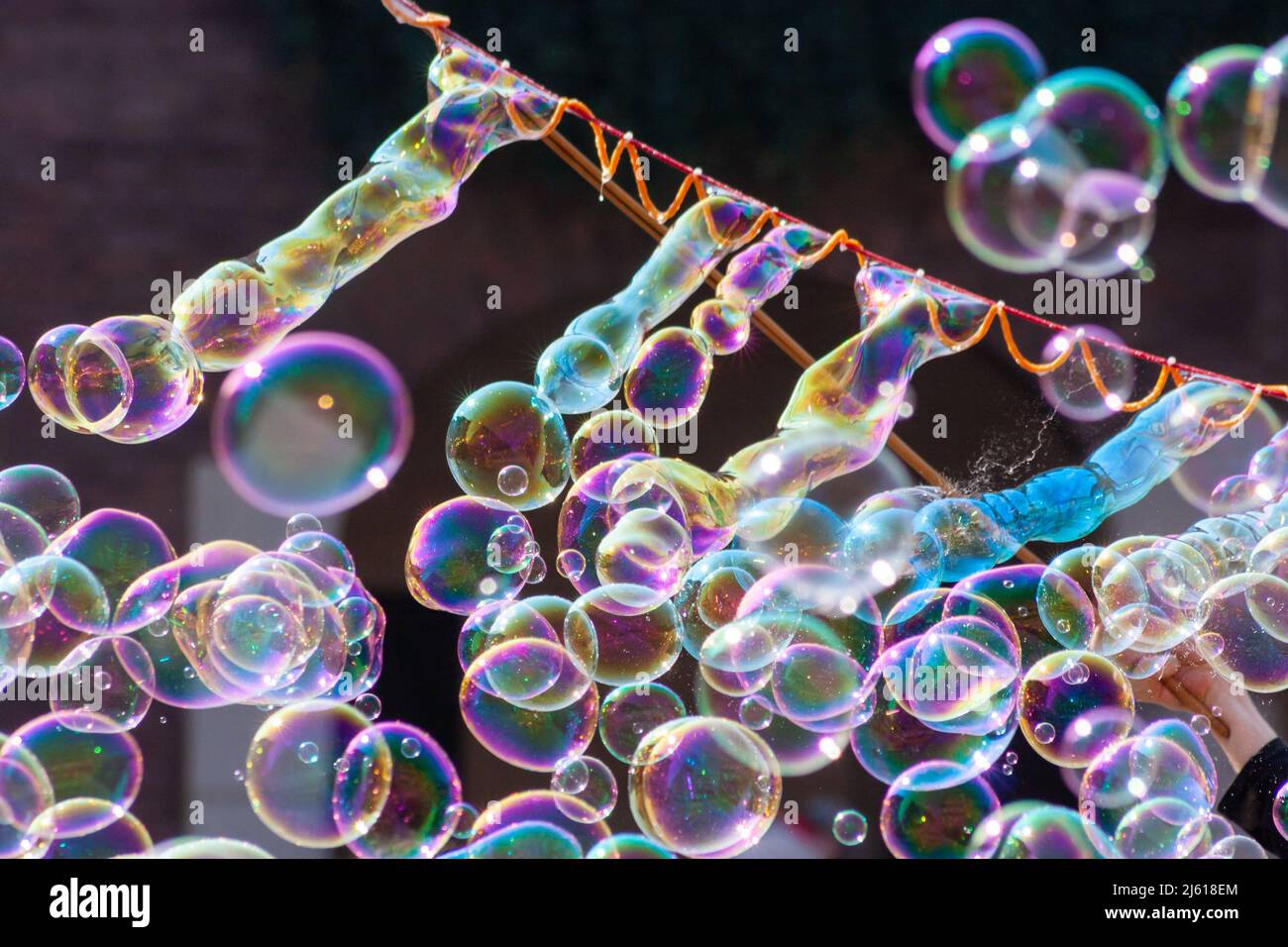 Gigantic soap bubbles shimmer and glimmer in the sun as colorful kids ...