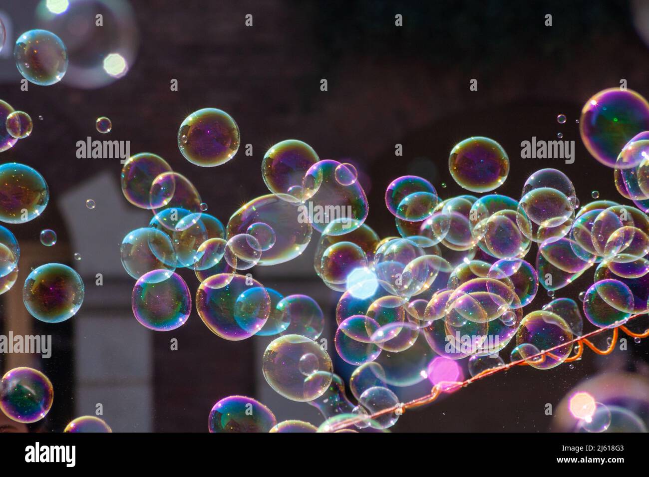 Gigantic soap bubbles shimmer and glimmer in the sun as colorful kids ...
