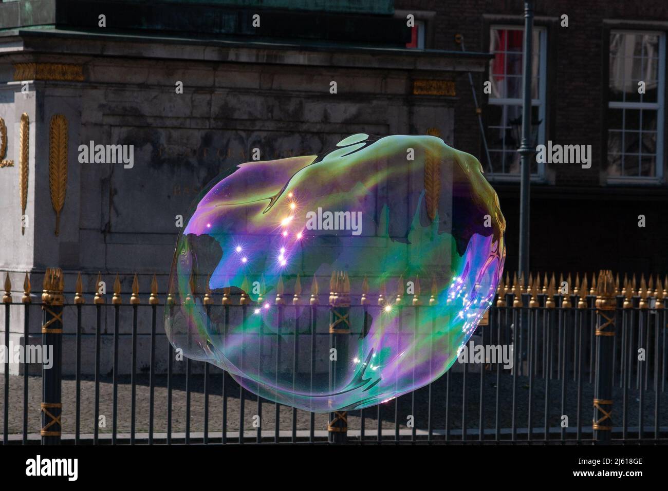 Gigantic soap bubbles shimmer and glimmer in the sun as colorful kids ...