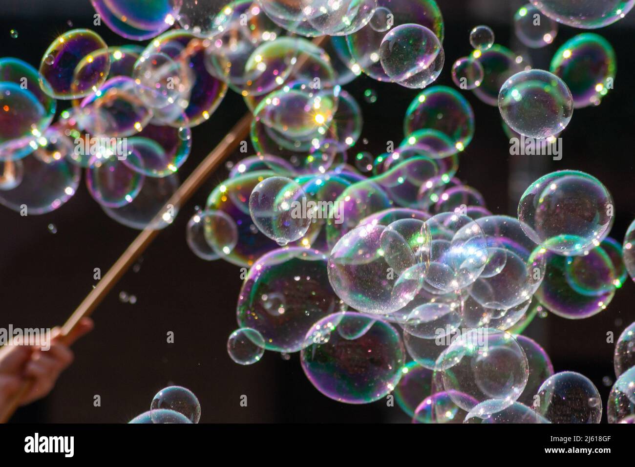 Gigantic soap bubbles shimmer and glimmer in the sun as colorful kids ...