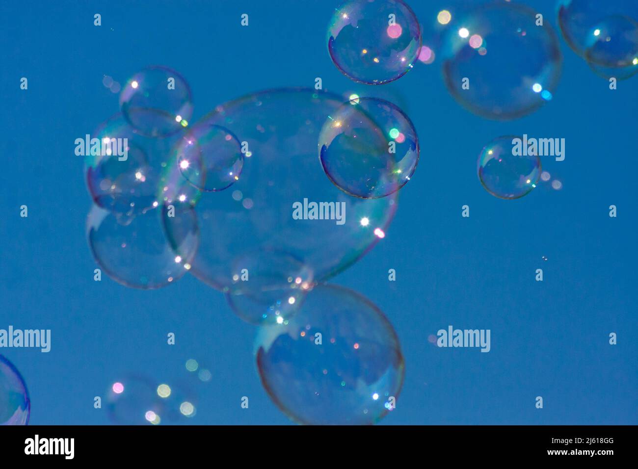 Gigantic soap bubbles shimmer and glimmer in the sun as colorful kids ...