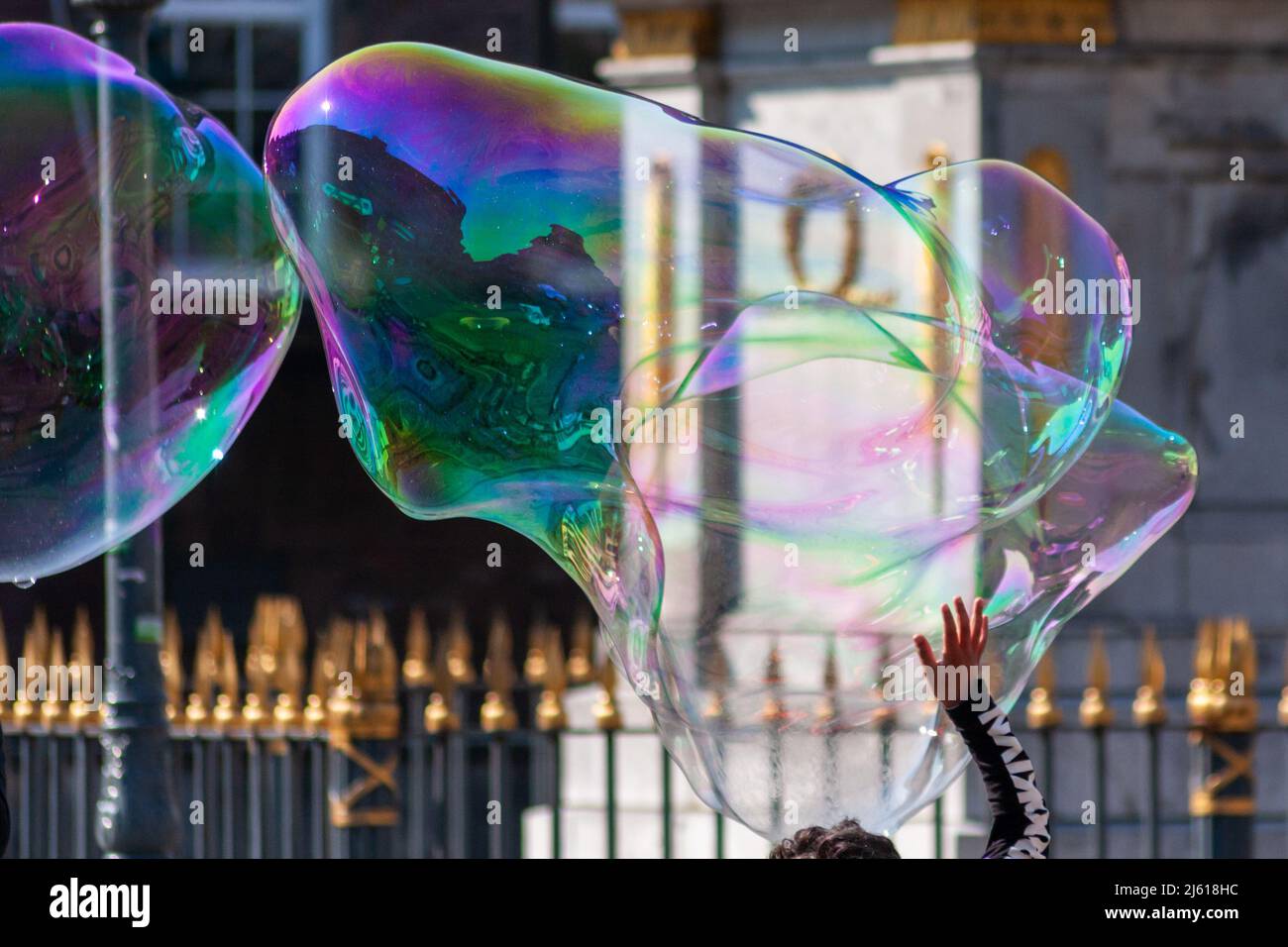 Gigantic soap bubbles shimmer and glimmer in the sun as colorful kids ...
