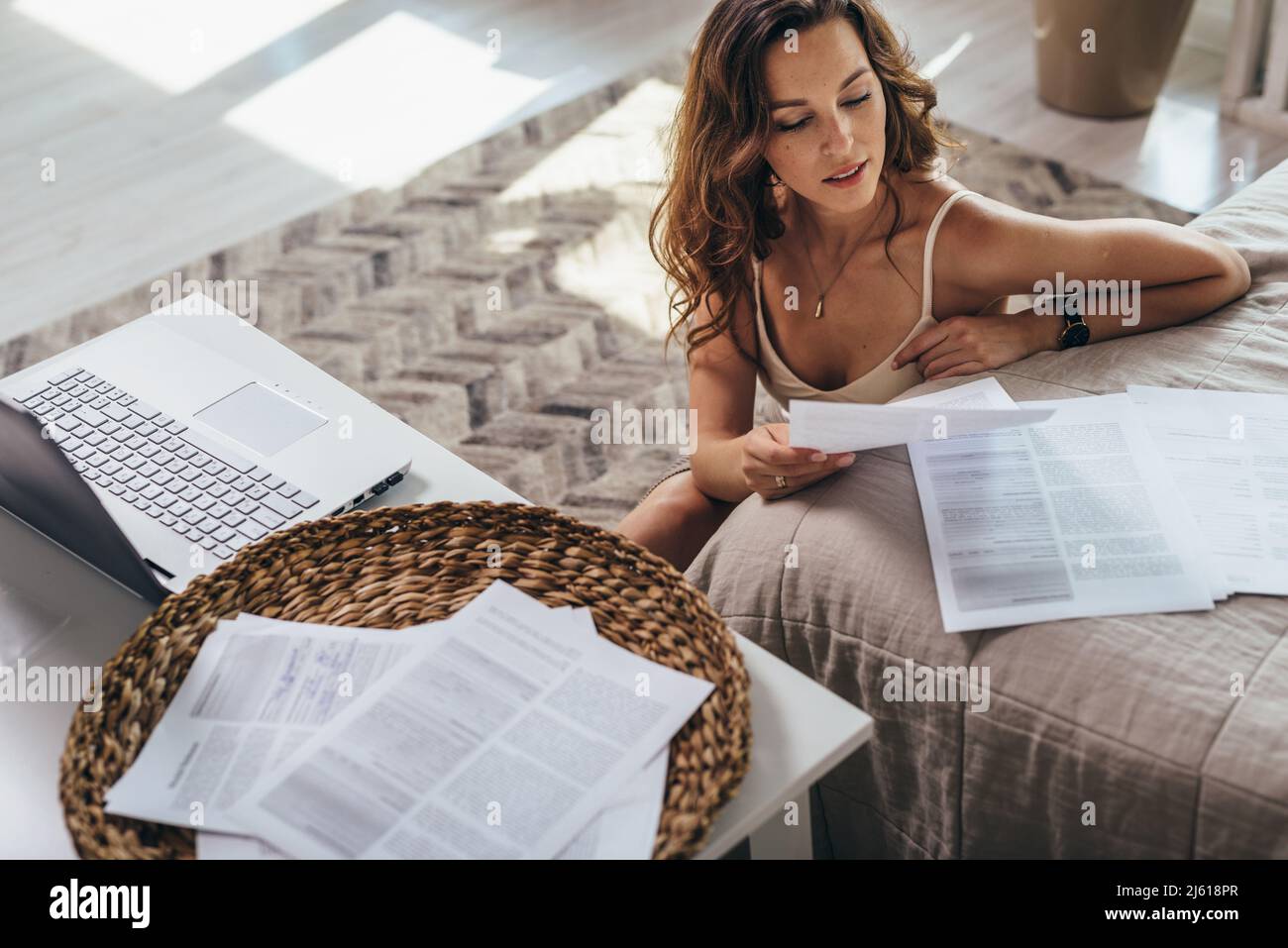 Woman works at home with documents. Papers are spread out on the bed Stock Photo - Alamy