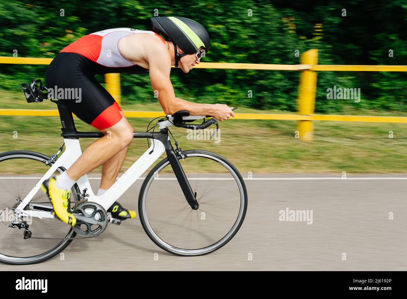 Side view of a man in a streamline helmet riding street racing bike on ...