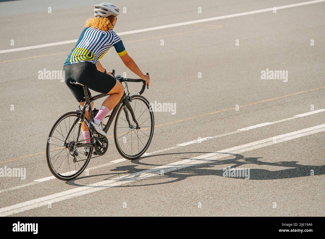 Back view of a woman riding her street racing bike on a road. On a ...