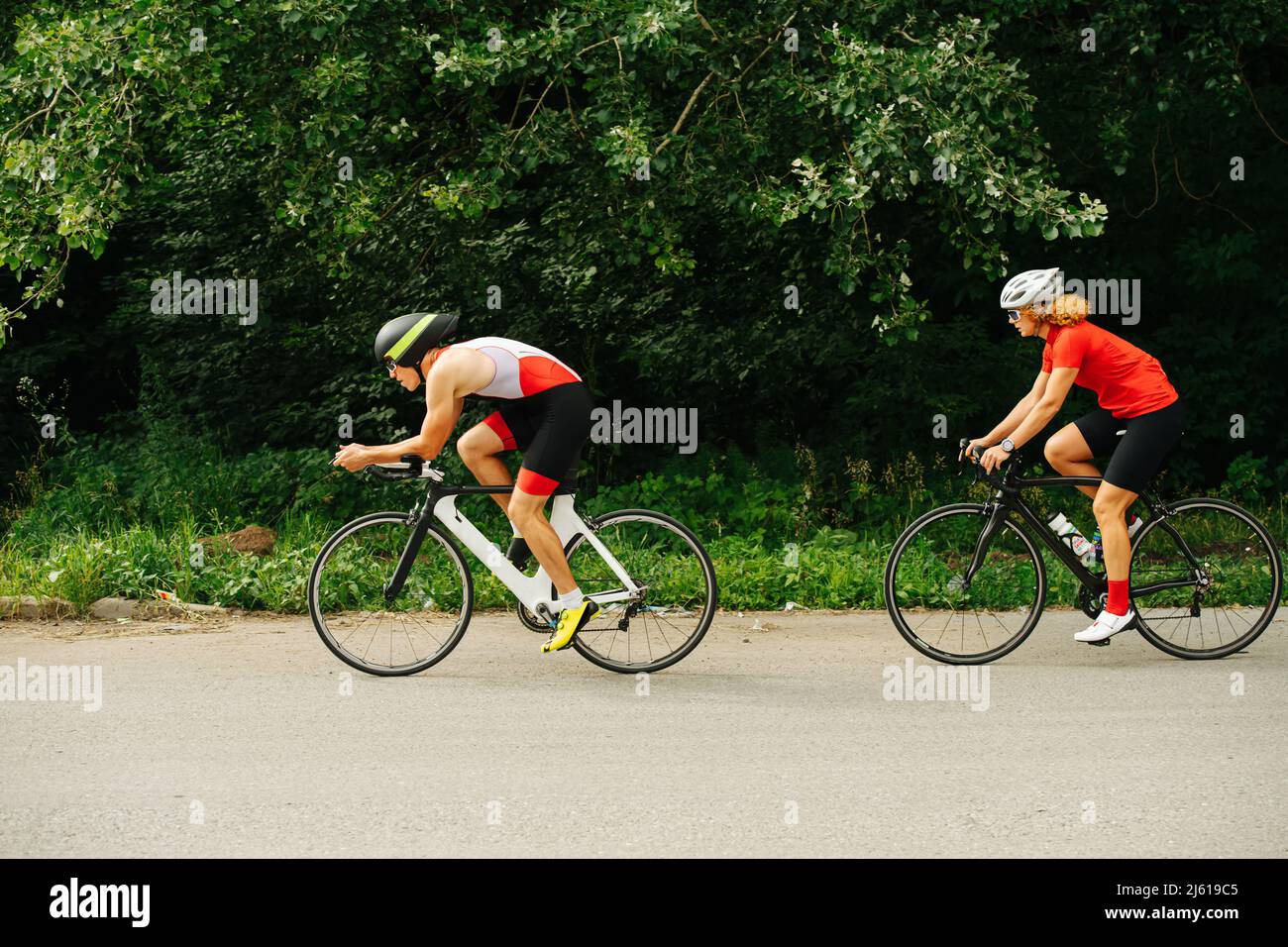 Side view of a couple riding street racing bike on a road through the ...