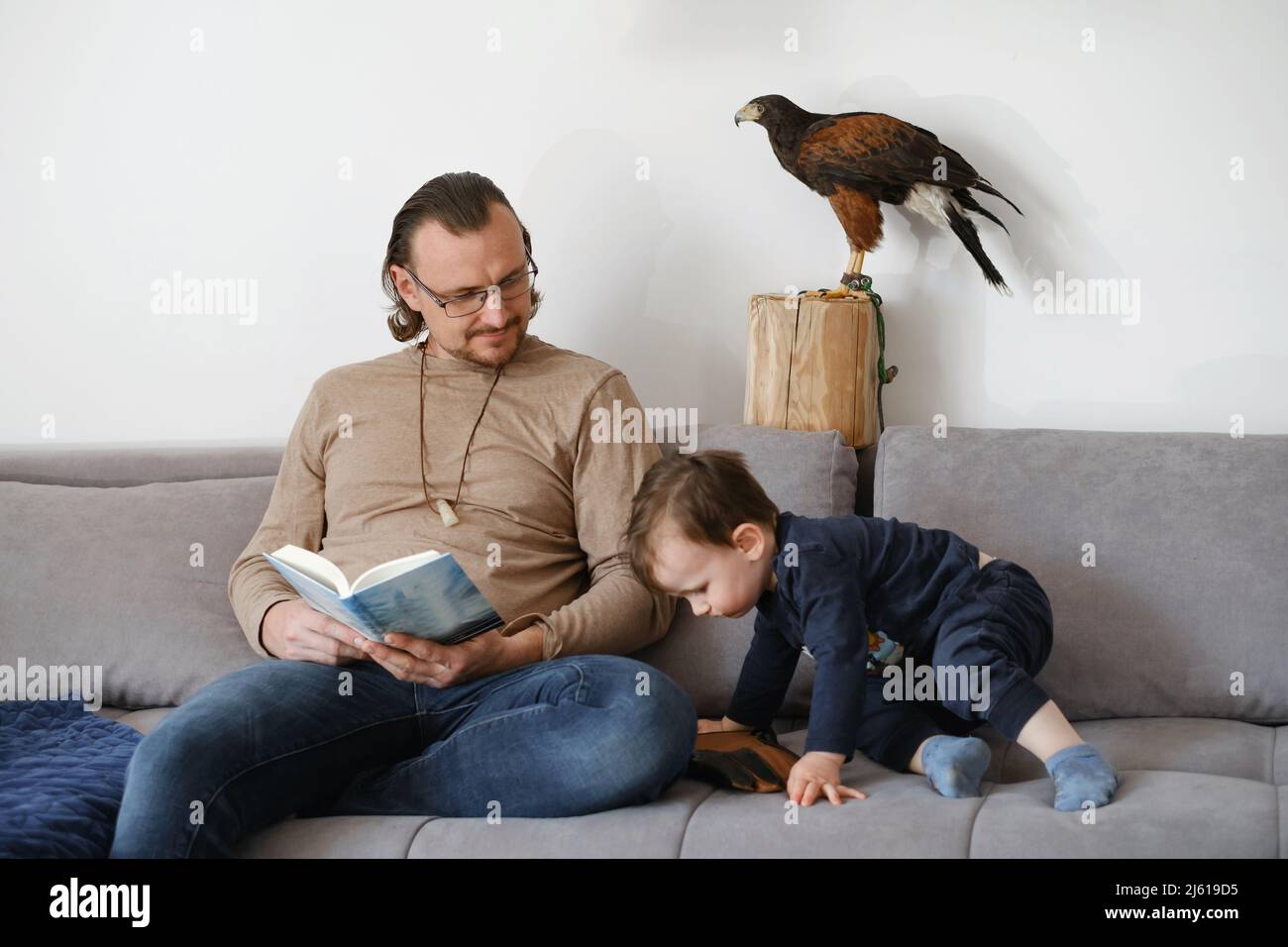 Father with child and wild bird buzzard sitting on the coach, reading ...
