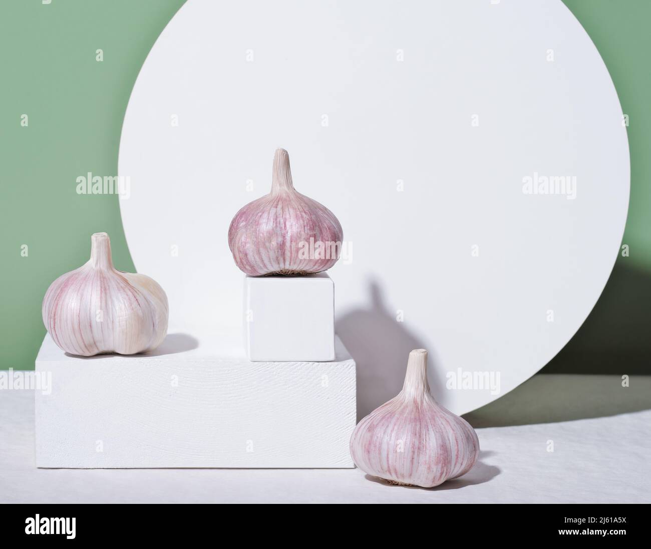 The whole unpeeled garlic on white geometric podium or pedestal. raw ...