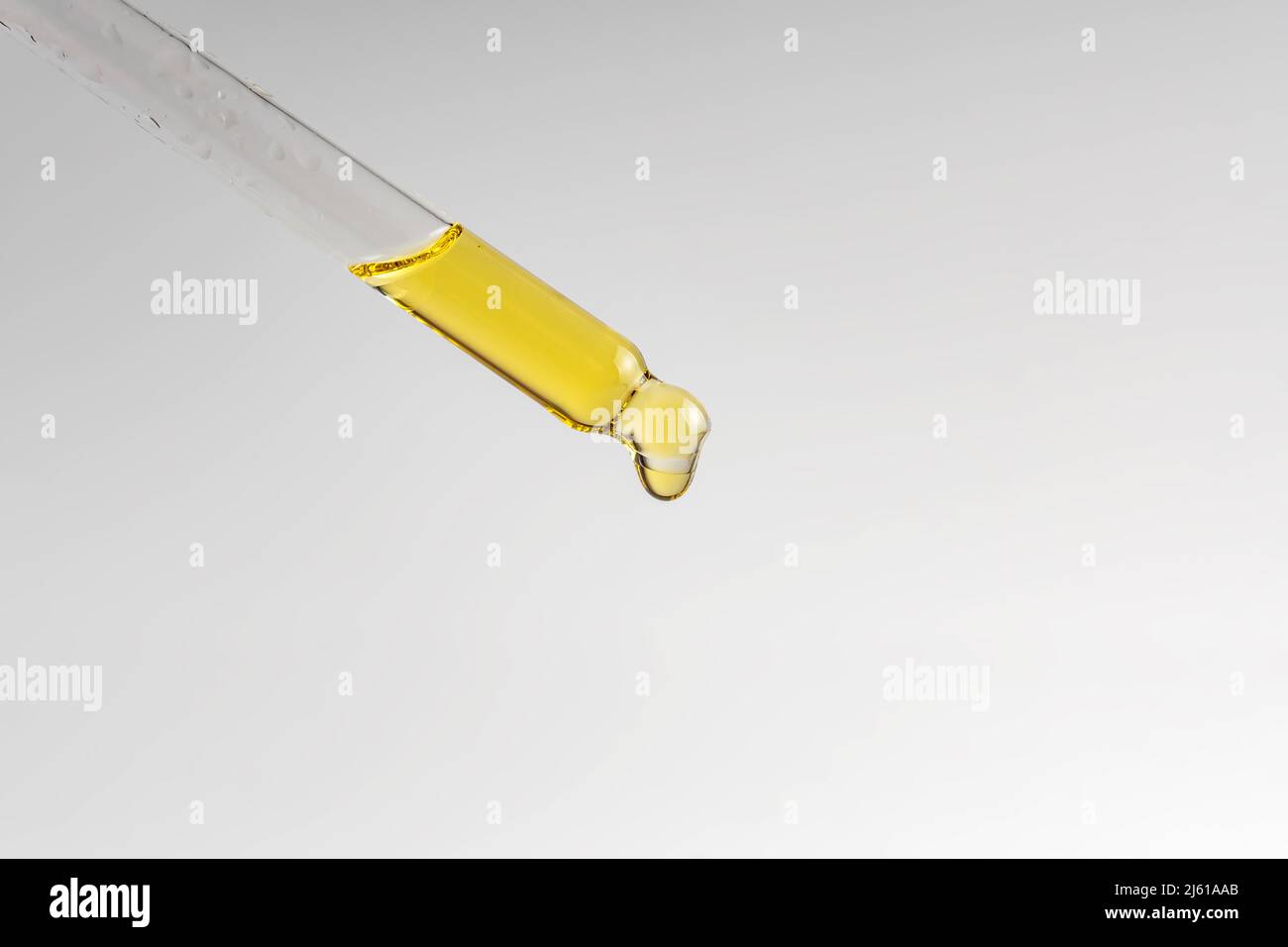 close up of pipette with pouring liquid serum on white background ...