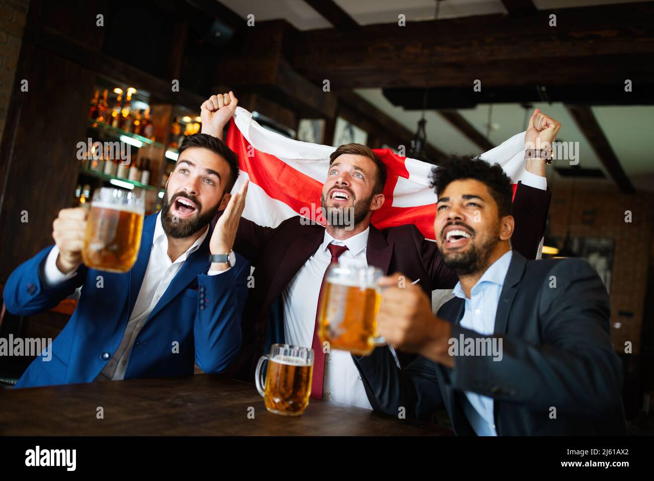 Men fans screaming and watching football on TV and drink beer in a pub ...