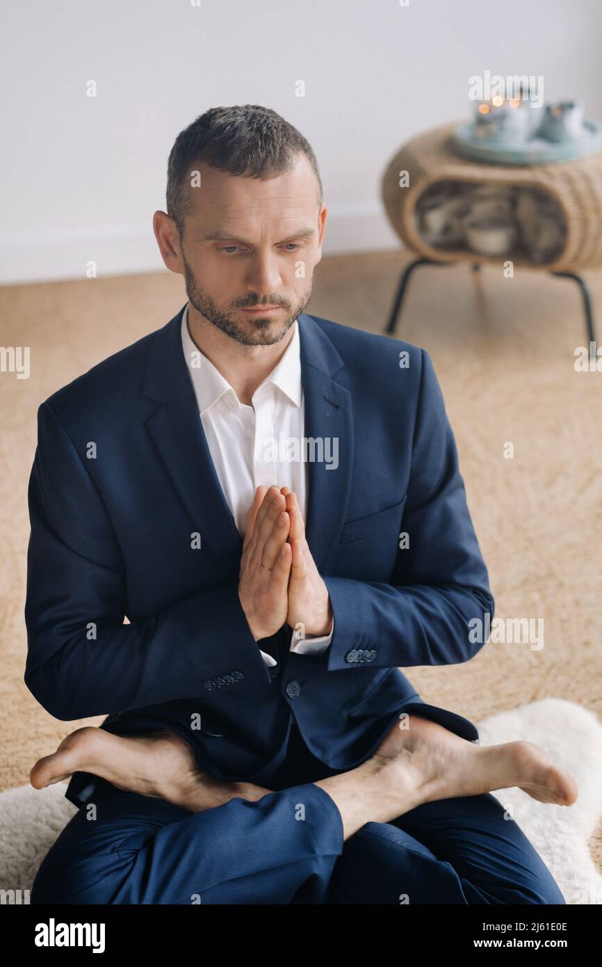 A man in a strict suit does Yoga while sitting in a fitness room Stock ...