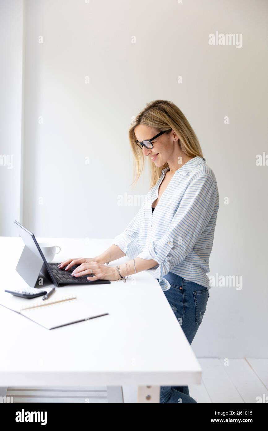 pretty young blonde business woman stands by her ergonomic height ...