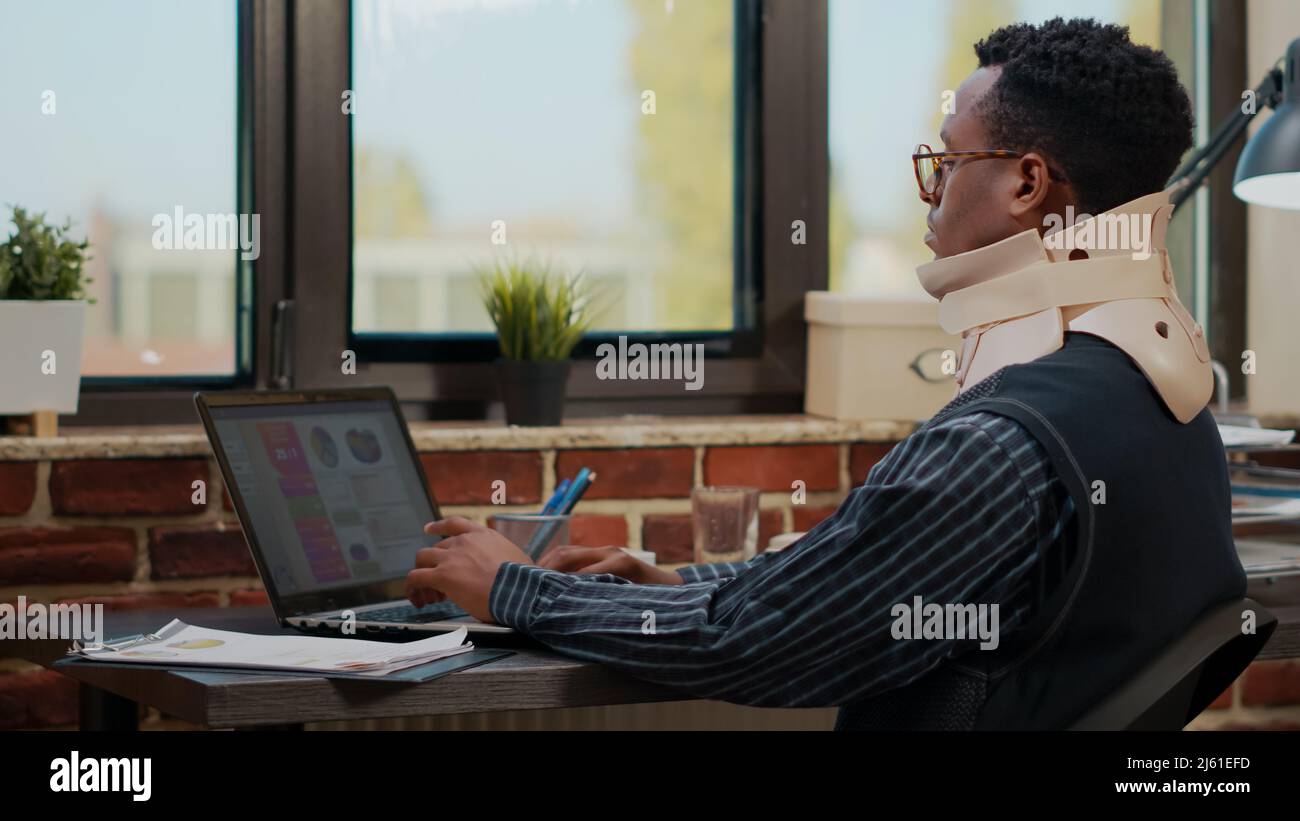 Injured worker with cervical collar using laptop to plan finance career ...