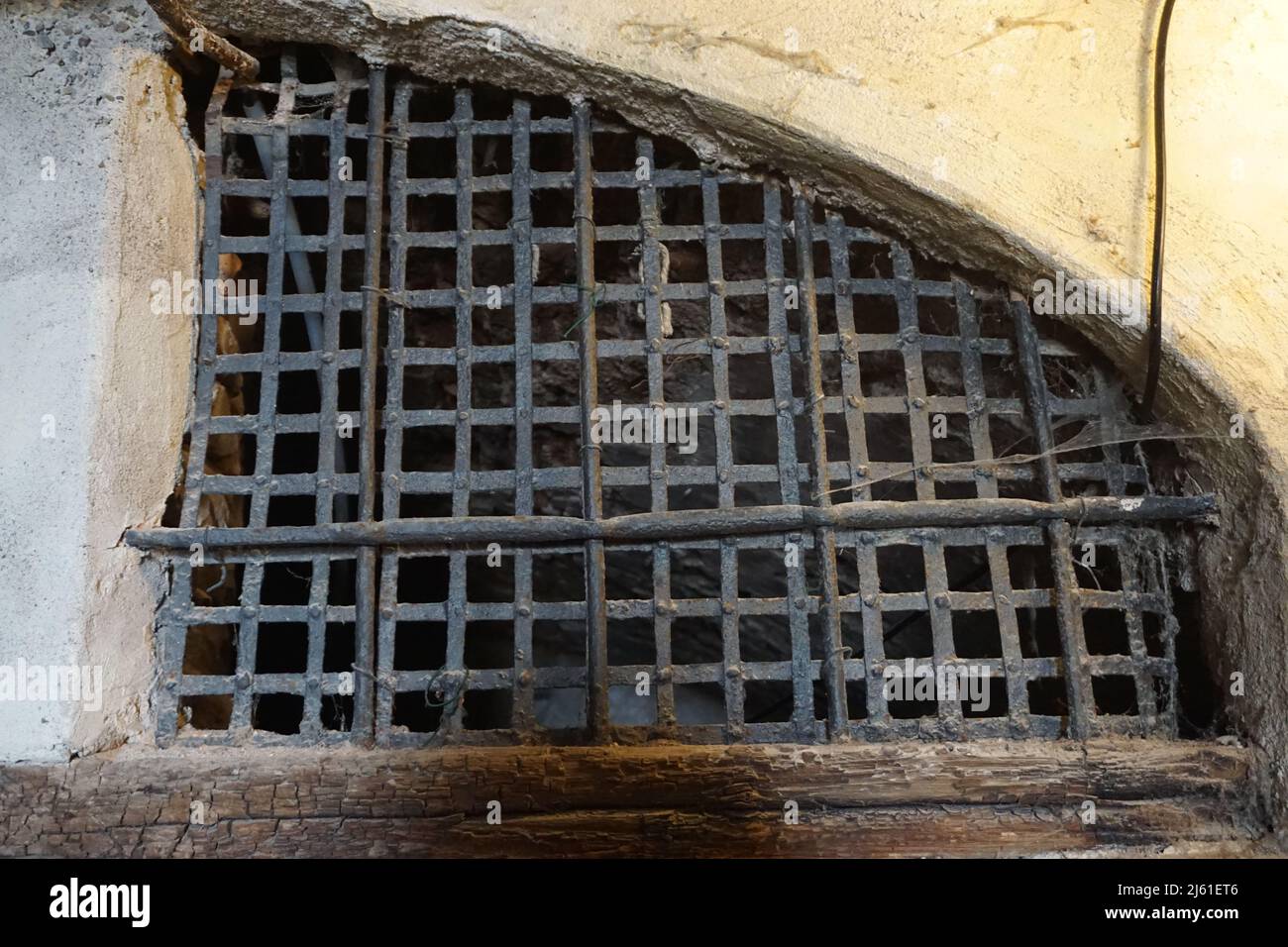 unusual curved window with metal grating on old stone wall Stock Photo ...