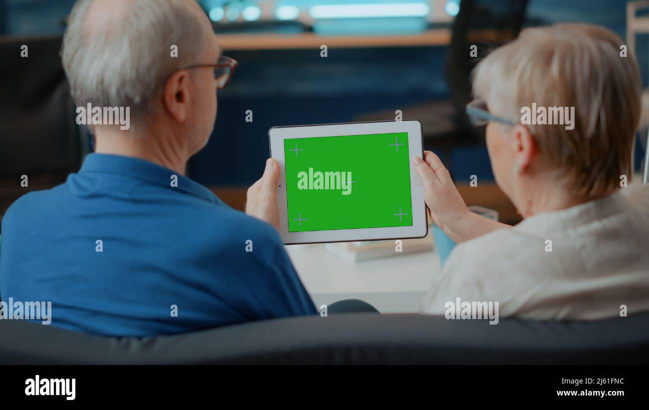 Senior people holding digital tablet with green screen in living room ...