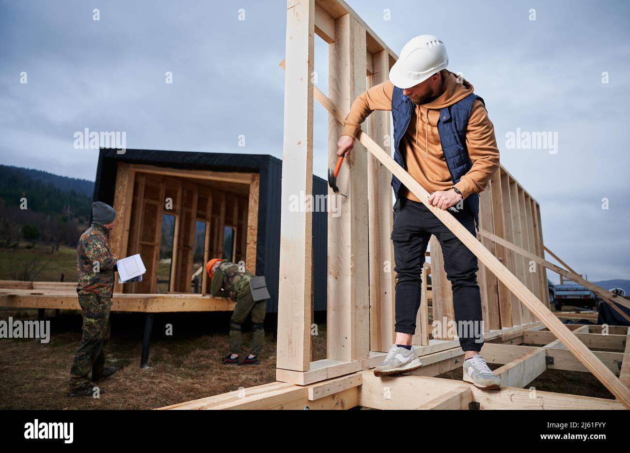 Man worker building wooden frame house on pile foundation. Carpenter ...