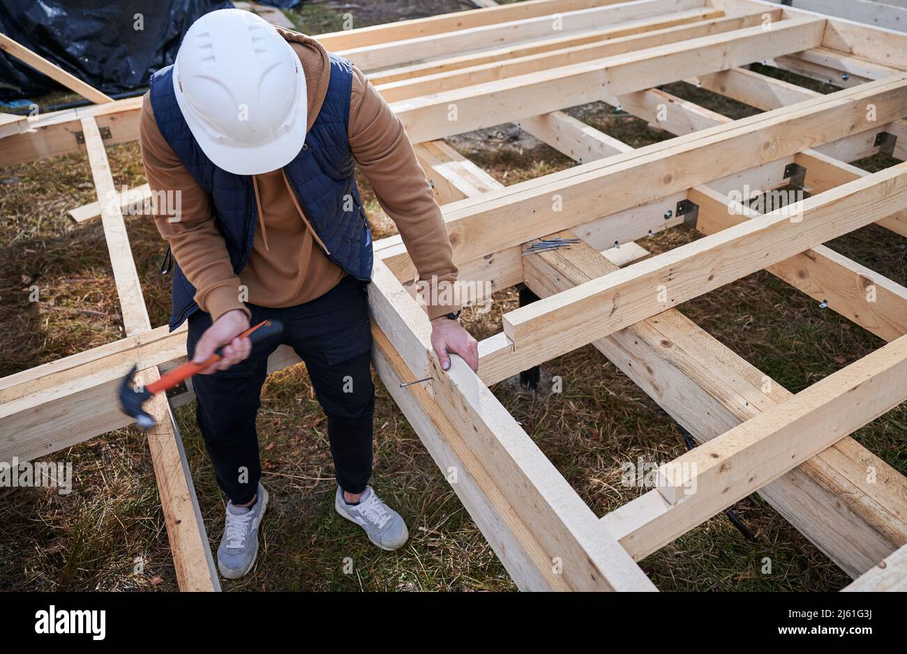 Man worker building wooden frame house on pile foundation. Carpenter ...