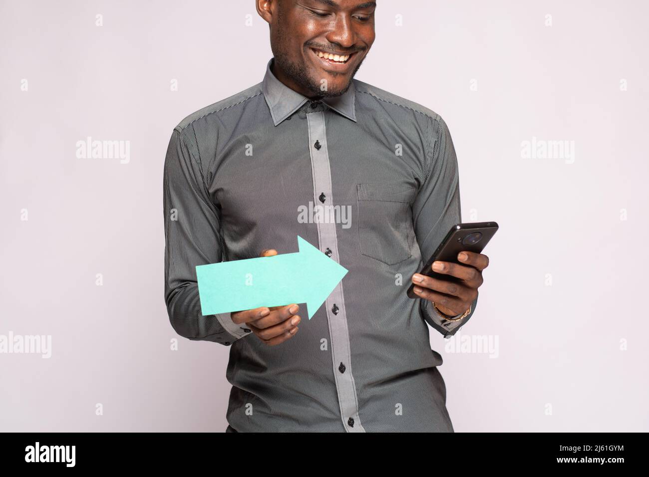 excited african man holding arrow pointing to phone Stock Photo - Alamy