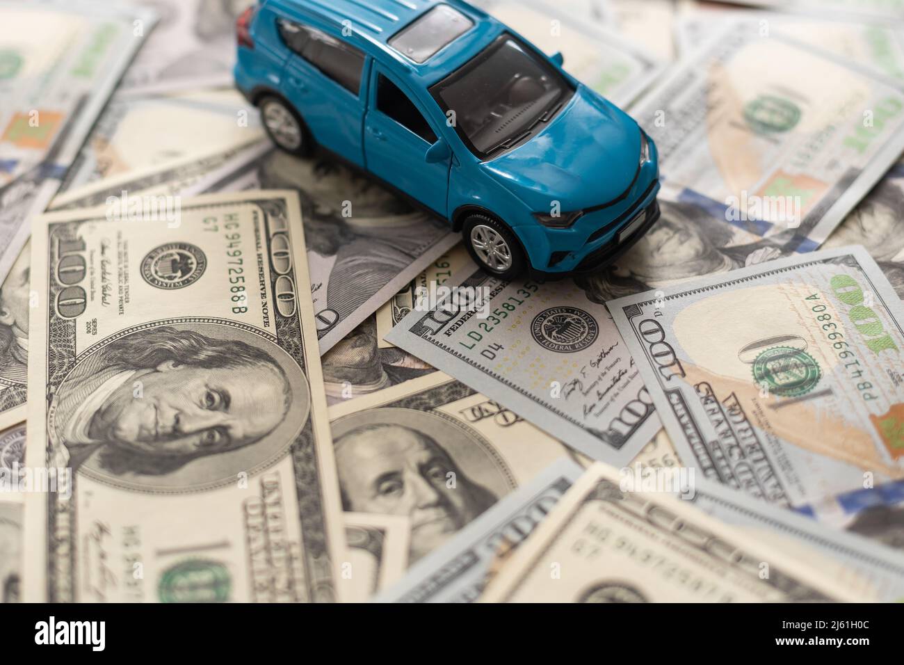 Small toy car on one hundred dollar banknotes as road, isolated on ...